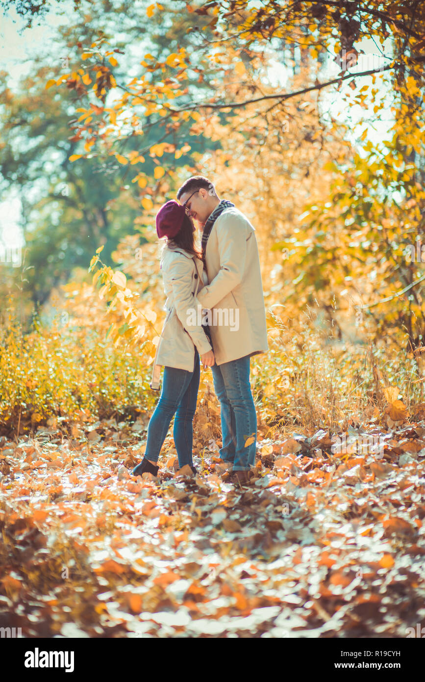 Loving couple is outdoors, cuddling and kissing in the park in autumn ...