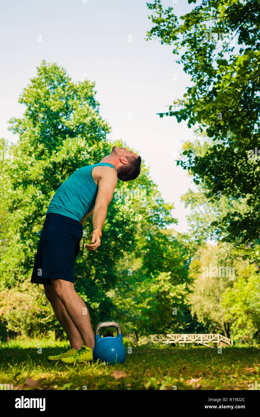 Fit man warming up before start to exercise with kettlebell into the ...