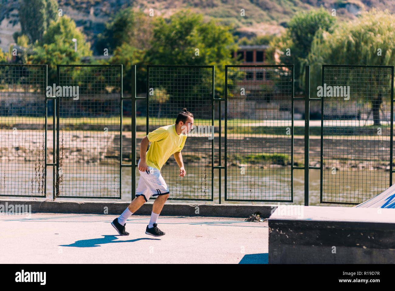 Training day of a young parkour man jumping over obstacles in skatepark ...