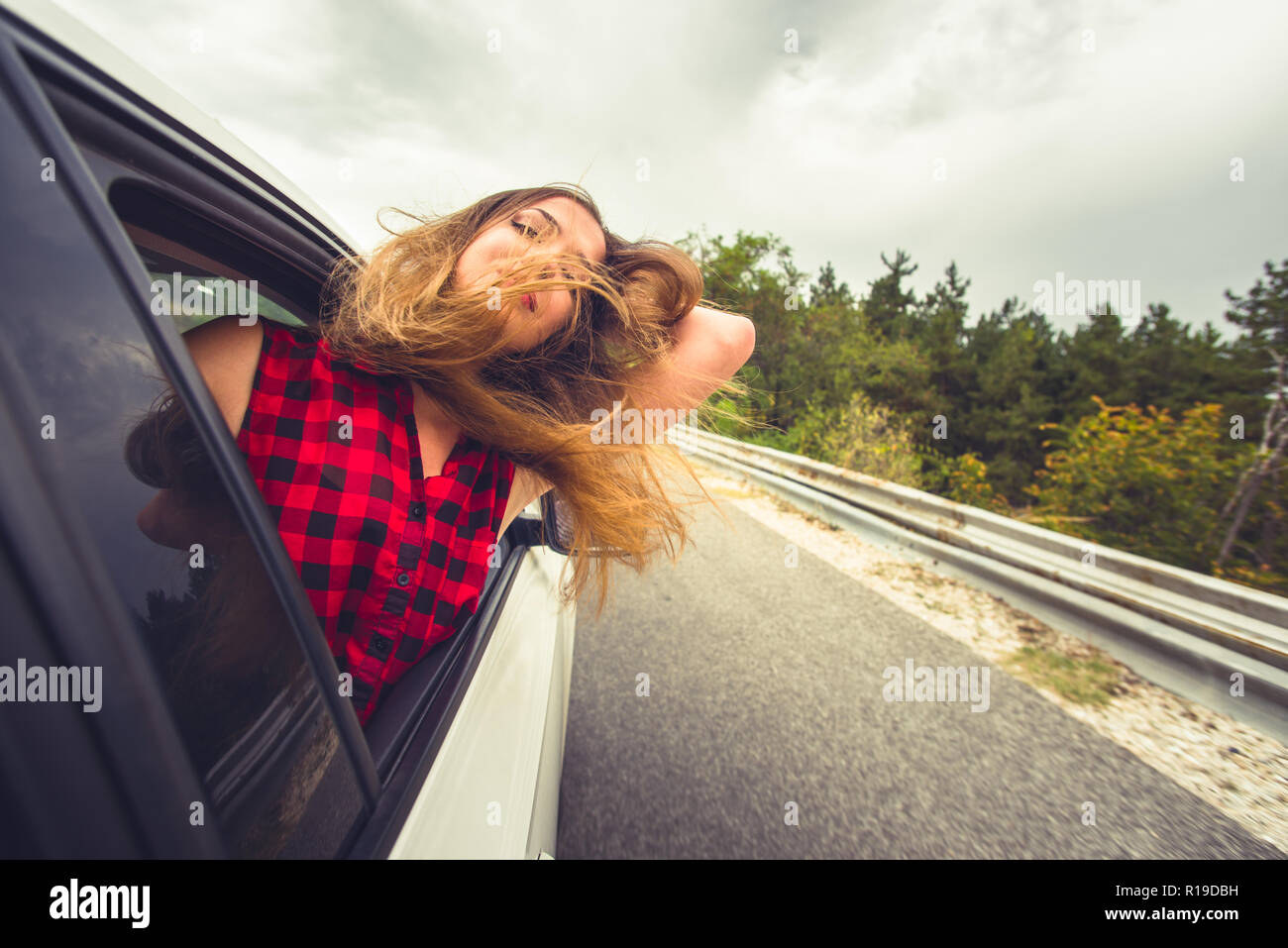 A female pulling her head out of a window while someone is driving her ...