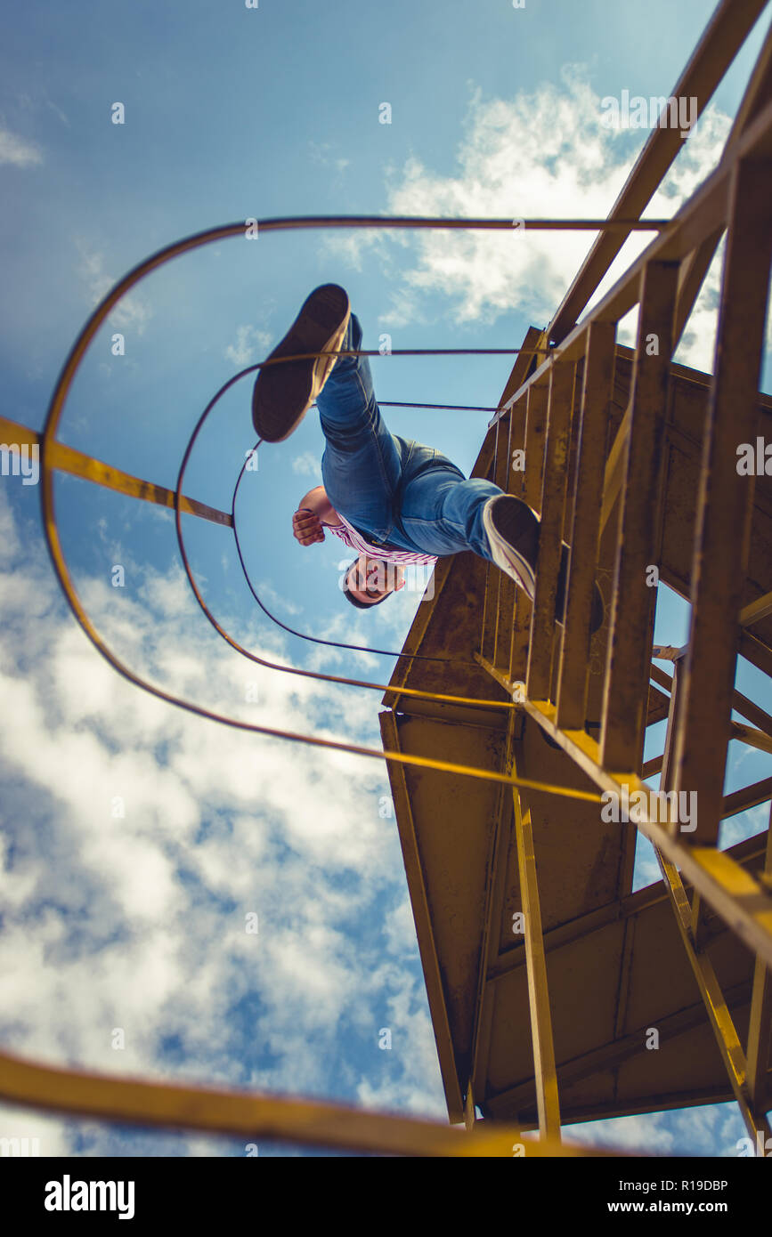 Man standing on one leg is climbing up on a iron constraction on a ...