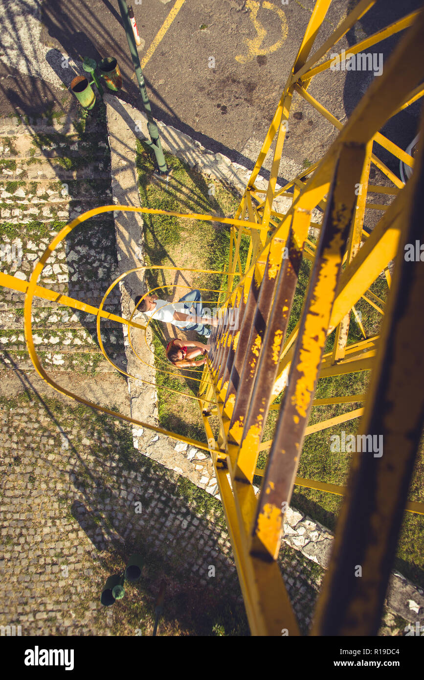 A boy and a girl trying to climb metal ladder and reach the top of the ...