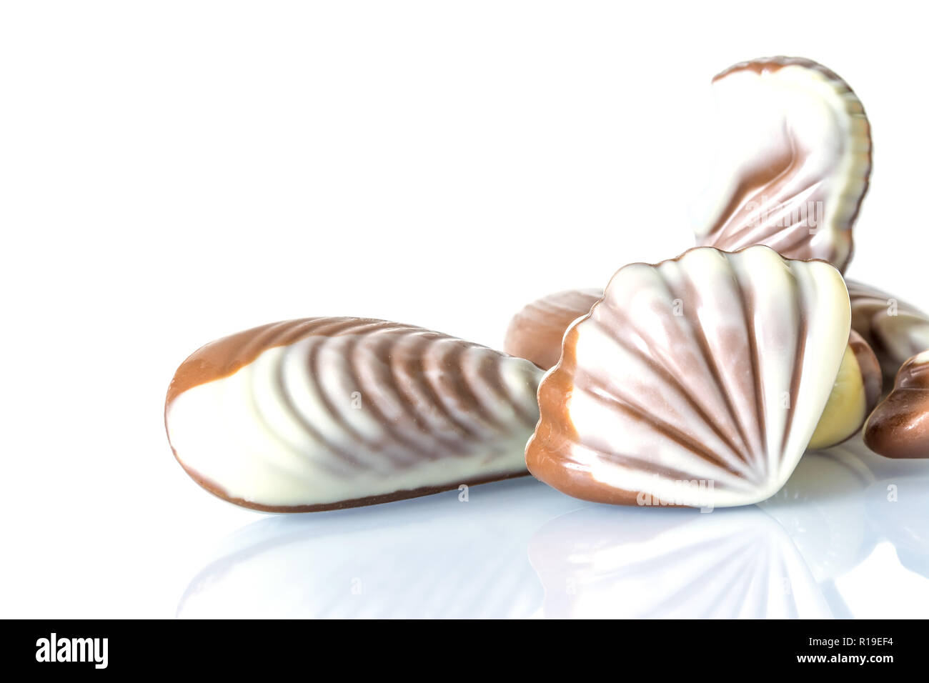 Chocolate candy in the form of sea shells on white table with ...