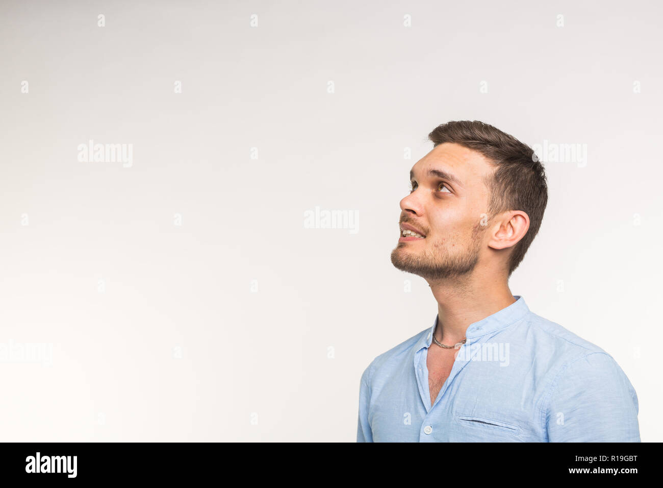 Expressions and people concept - Handsome cheerful young man looking up ...