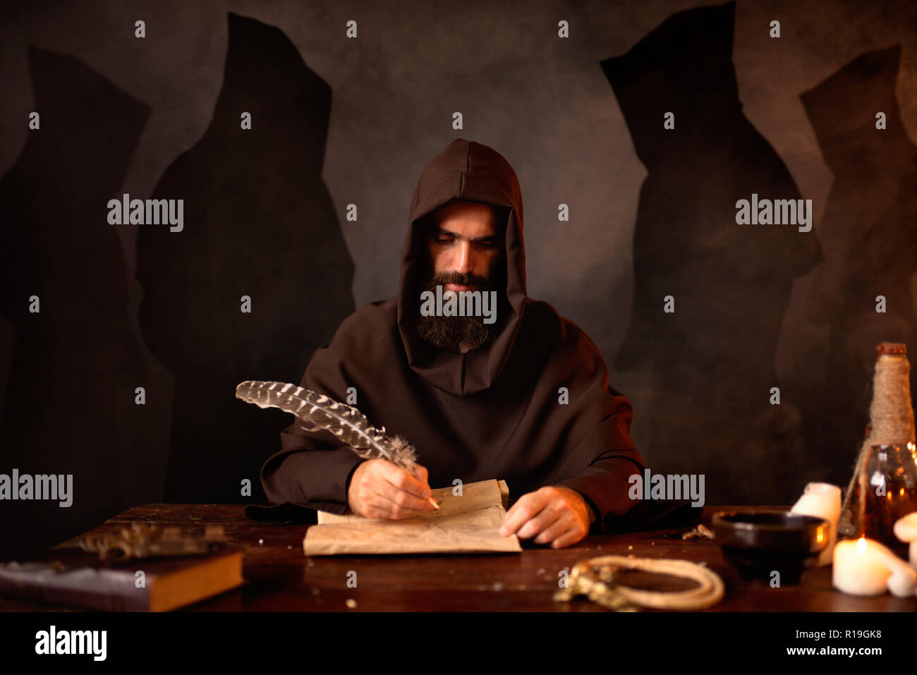 Medieval monk in robe makes notes in the secret scripture with a goose ...