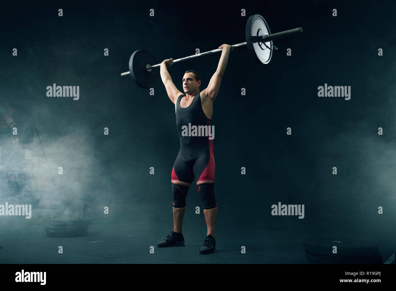 Strong weight lifter in sportswear takes a weight, powerlifter with ...