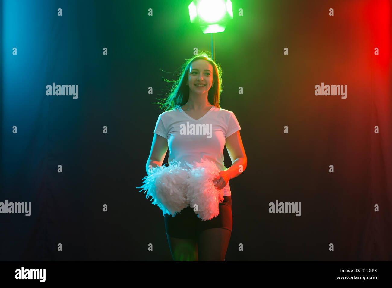 Portrait of cheerleading young woman dancing with pom-poms Stock Photo ...