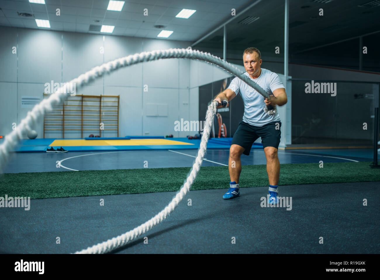 Male athlete with ropes in gym, crossfit workout. Cross fit training ...