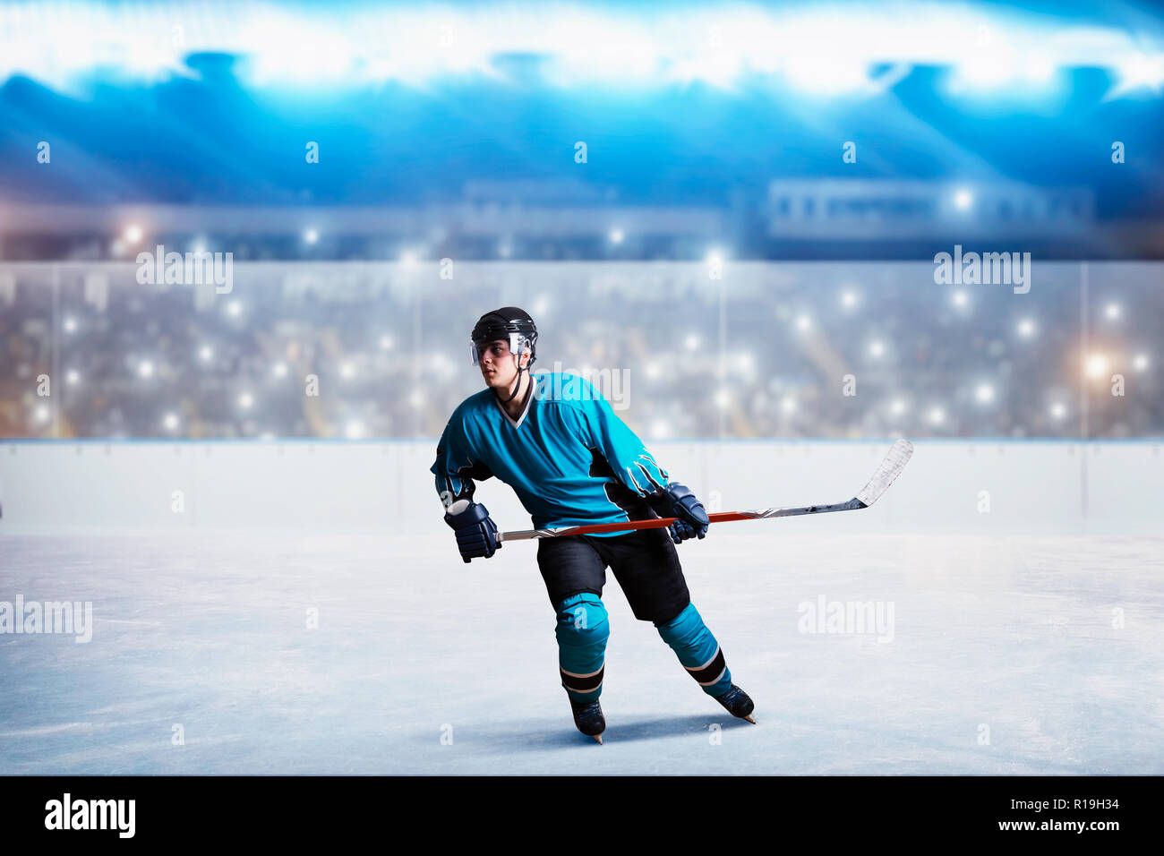 A hockey player on ice in action, arena spotlights and tribunes with ...