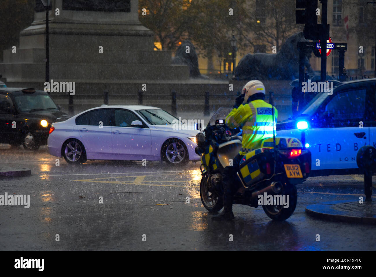 Police motorcyclist officer in heavy rain in Trafalgar Square stopping ...