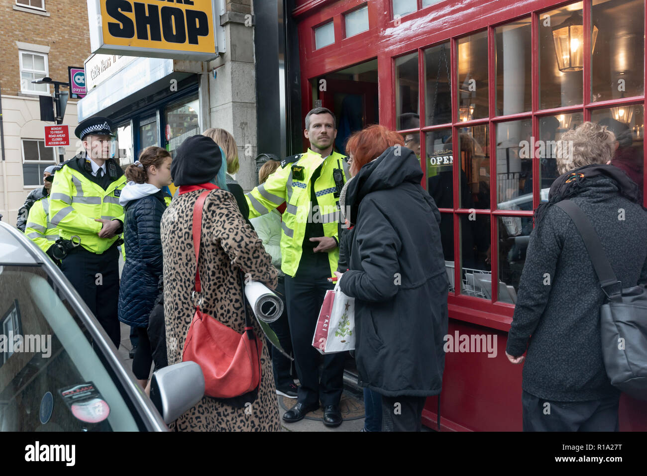 London, UK. 10th November 2018. Police officers escort a family group ...