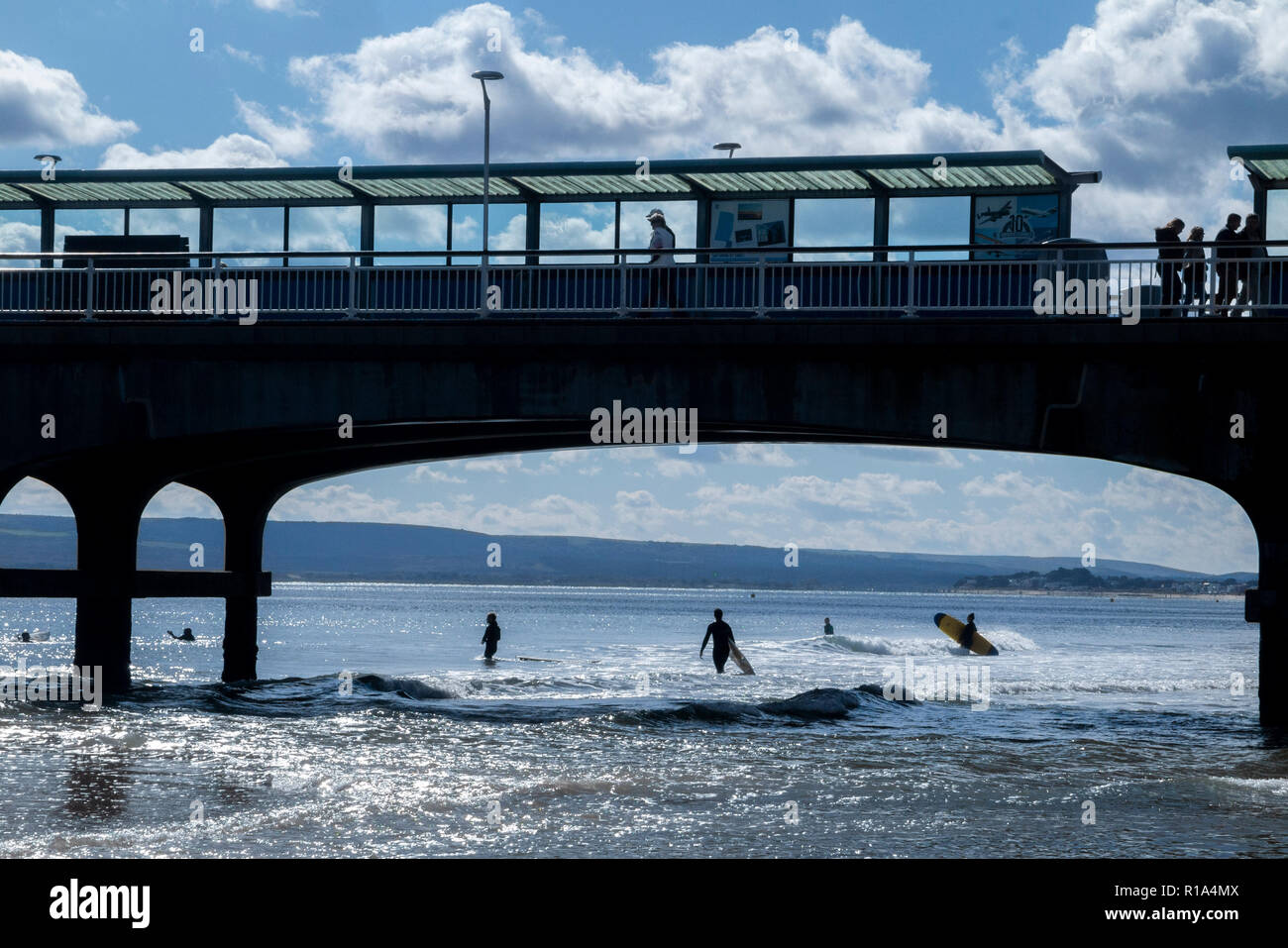 Surfers in the sea on Bournemouth beach in high summer, below the ...