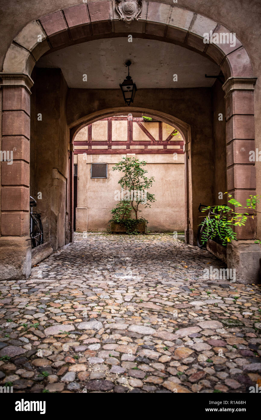 Arched entrance to courtyard on old European building with cobblestones ...