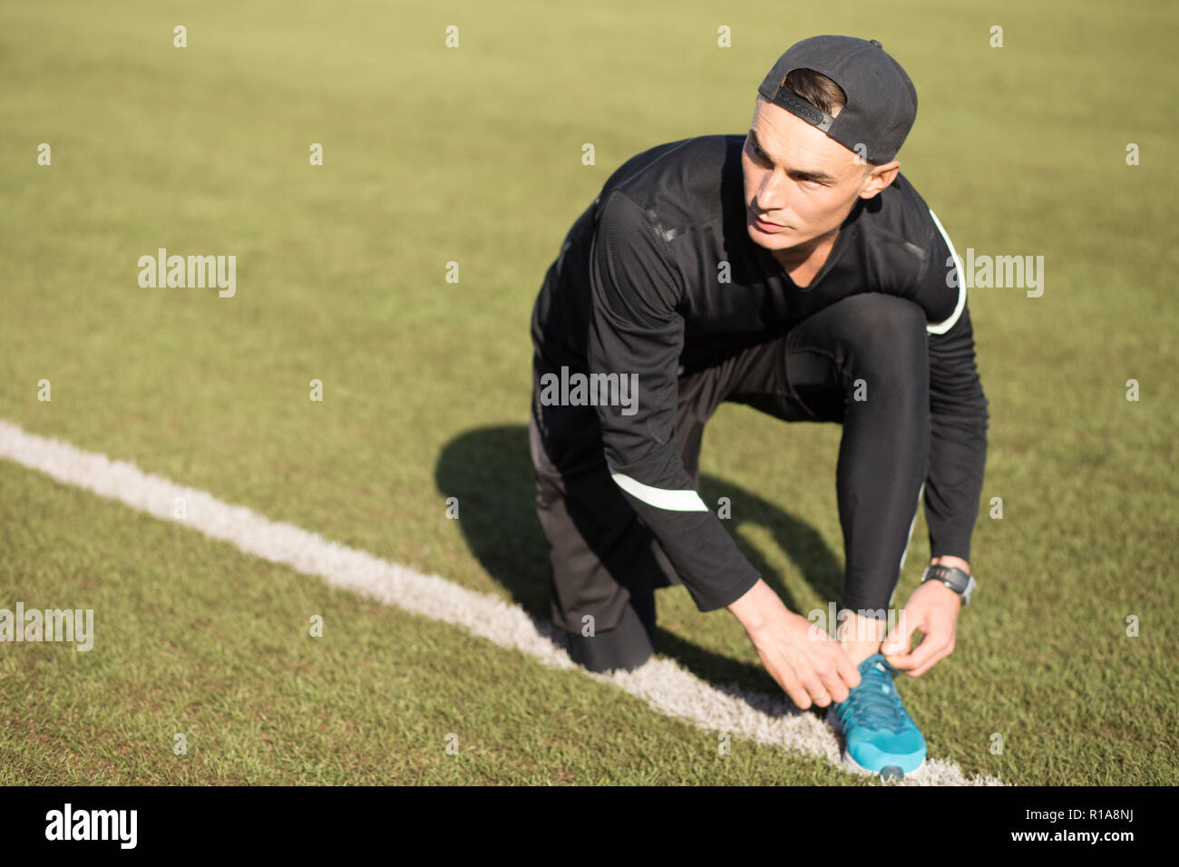 handsome runner tying the lace before the race Stock Photo - Alamy