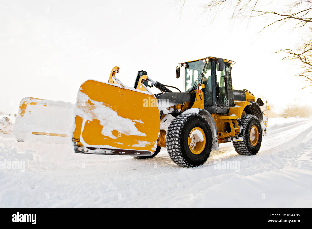A big yellow snow plow cleaning a road Stock Photo - Alamy