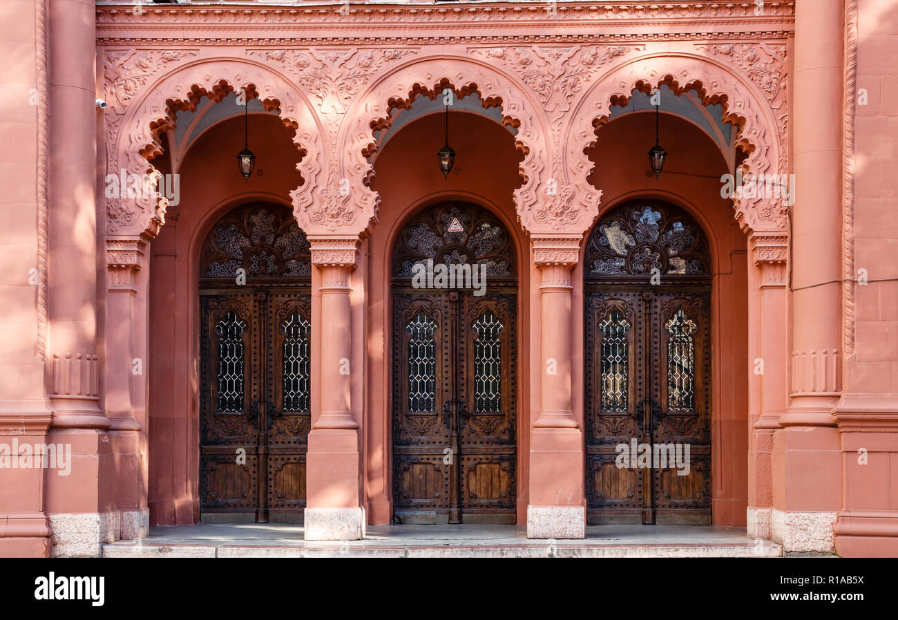 Three arched wooden doors in a row on the red facade of Synagogue of ...
