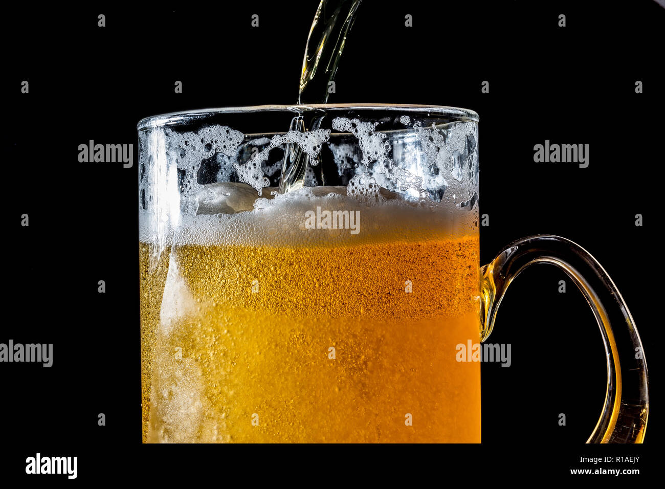 Stream Of Beer Being Pouring Into A Glass With Beer And Foam Isolated