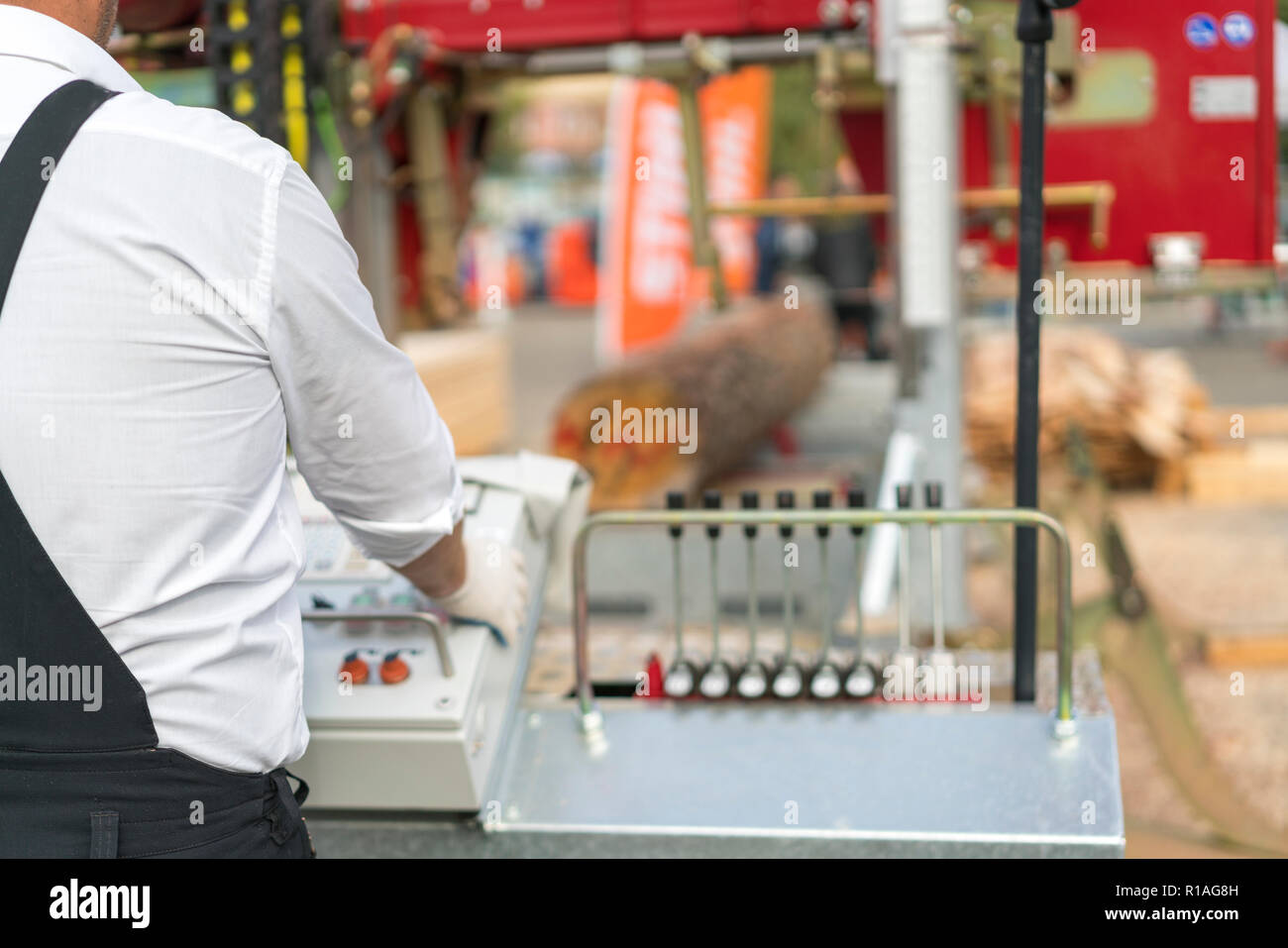 Worker pressing buttons on CNC machine control board in factory ...