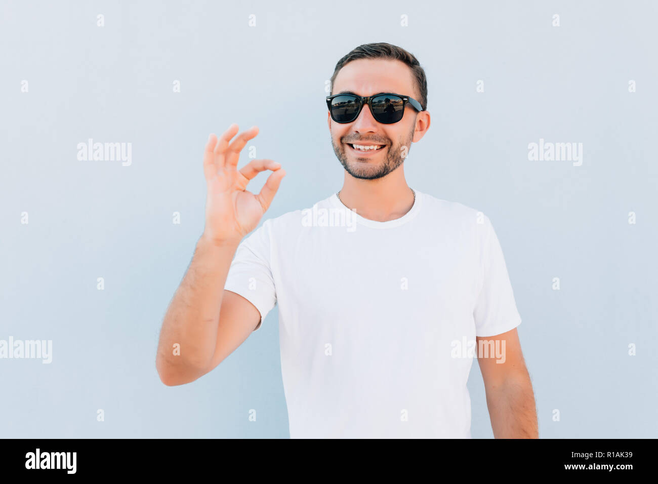 Young smiling man having happy look, gesturing, showing OK sign or ...