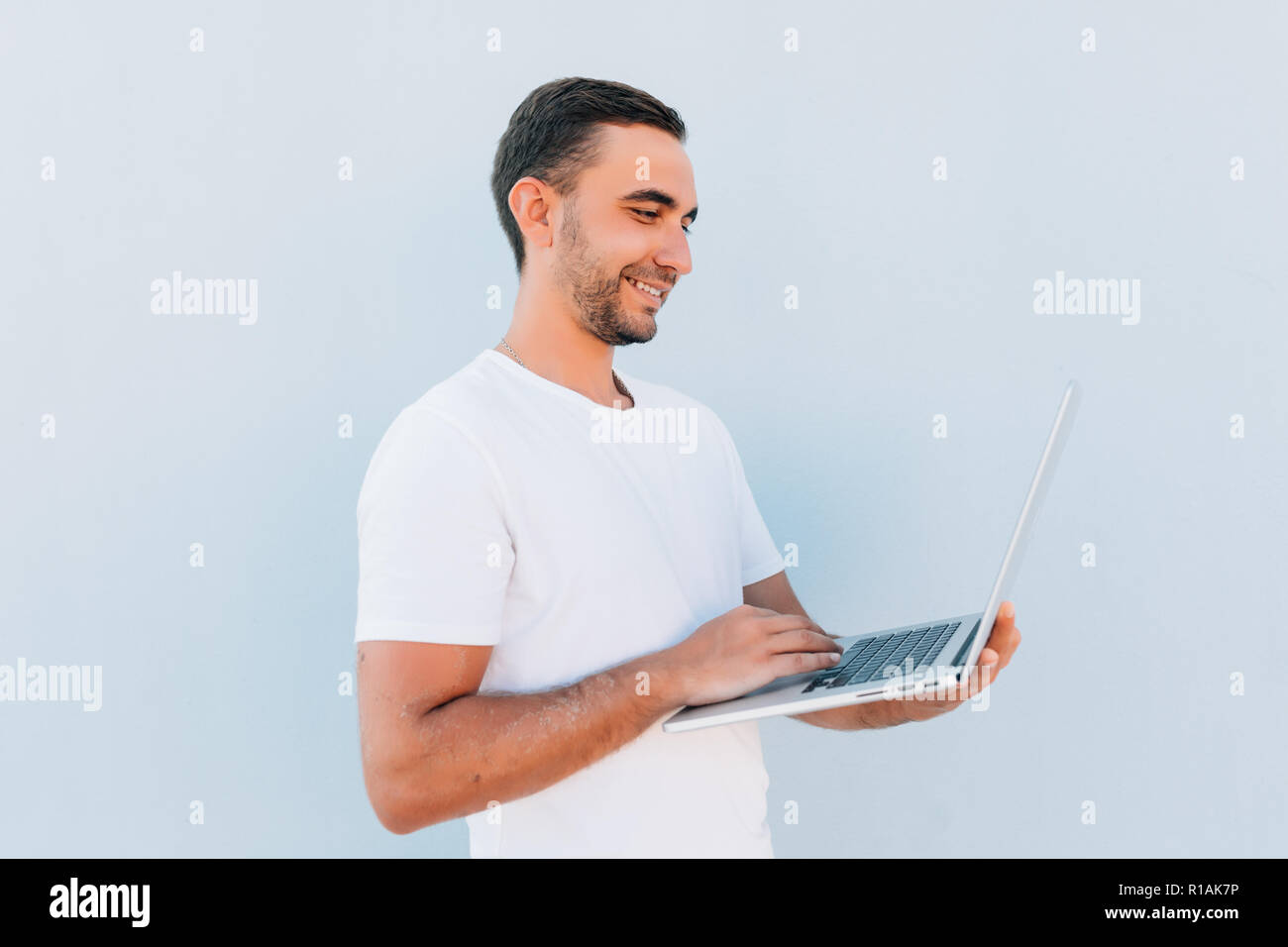 Portrait of handsome man in casual t-shirt holding silver notebook and ...