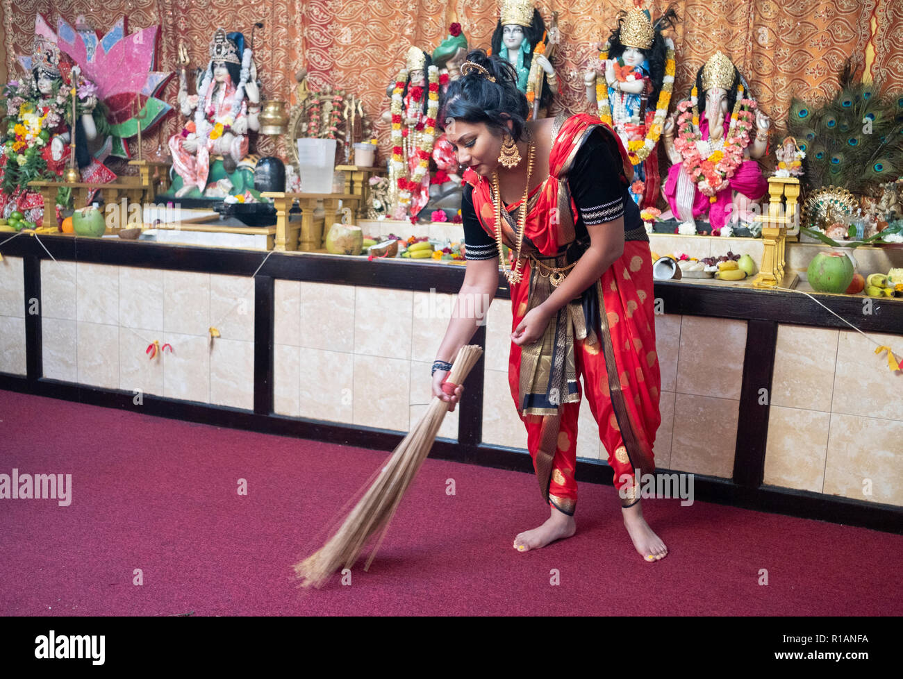 A Hindu priestess in a beautiful sari sweeps after services with a ...