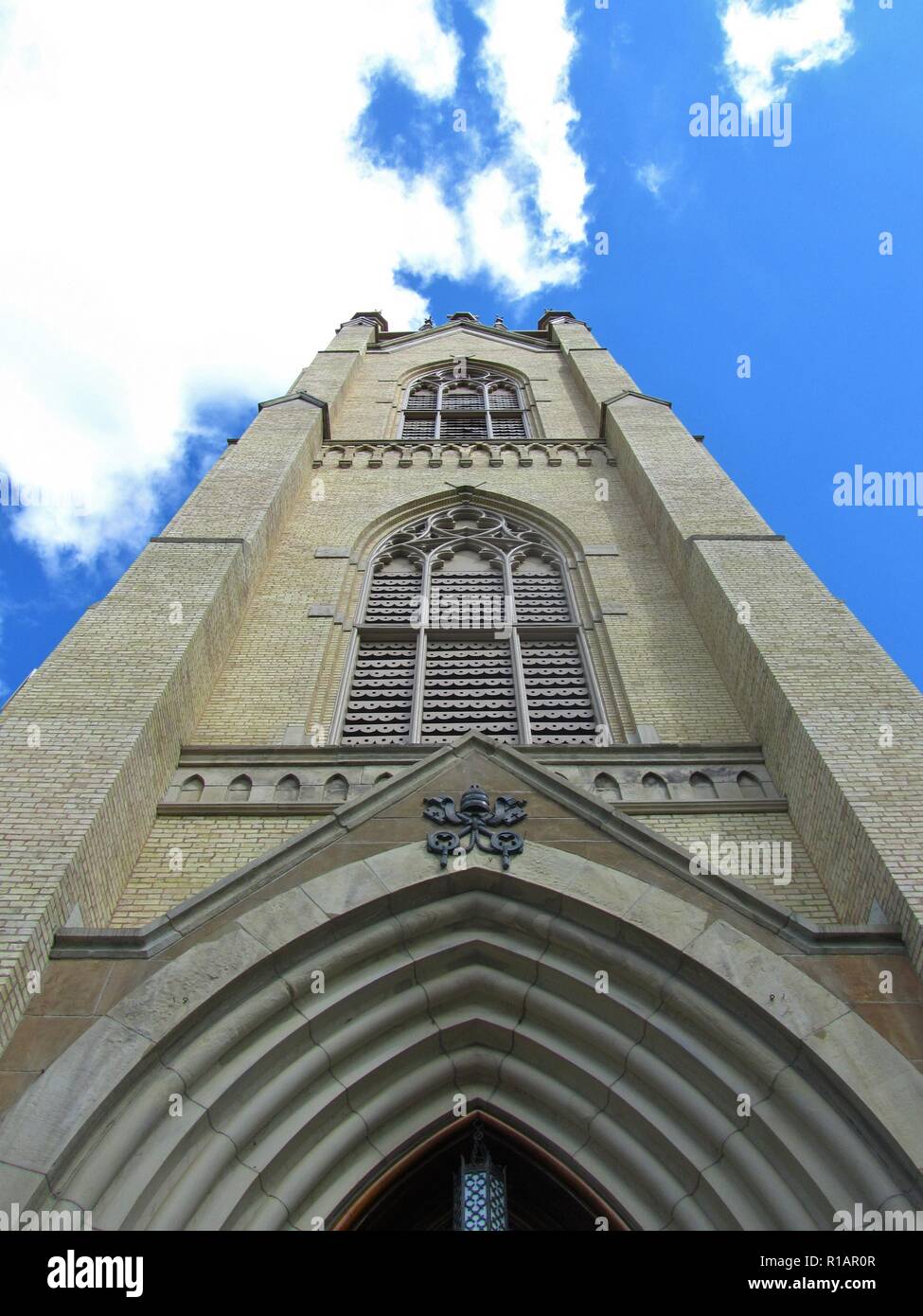 Brick church tower looking up from the front door with blue sky and ...