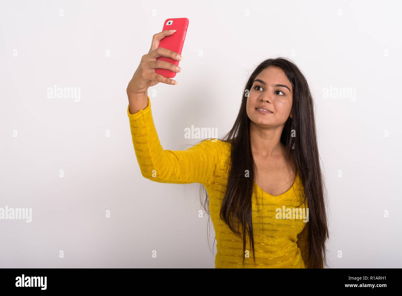 Studio shot of young happy Indian woman smiling while taking sel Stock ...