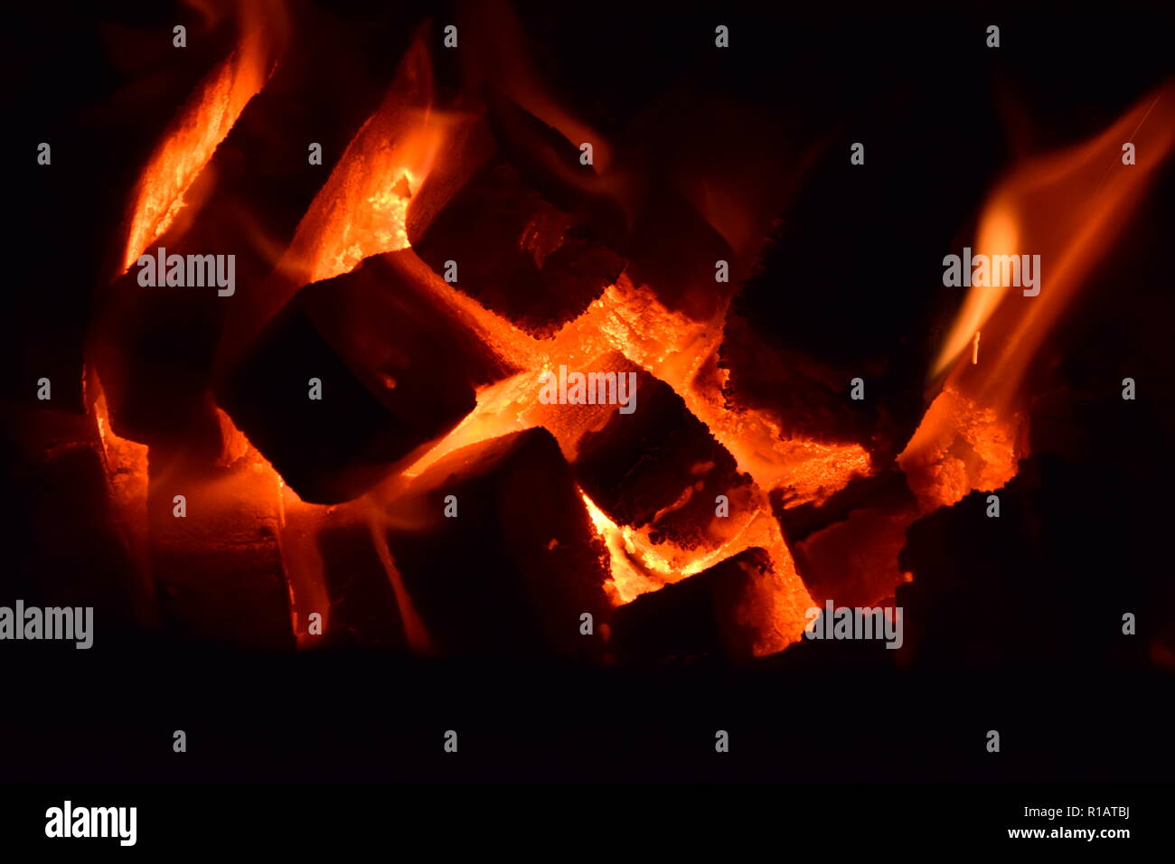 Close up of Brown Coal Briquettes on fire with red yellow flames inside ...