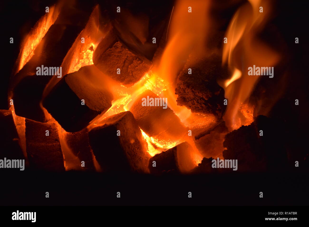 Close up of Brown Coal Briquettes on fire with red yellow flames inside ...