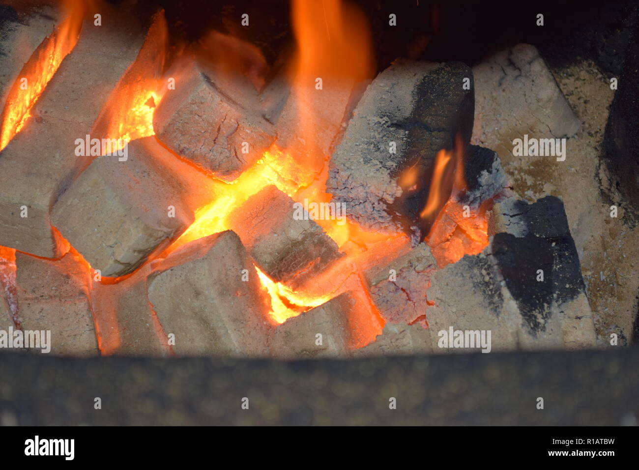 Close up of Brown Coal Briquettes on fire with red yellow flames inside ...
