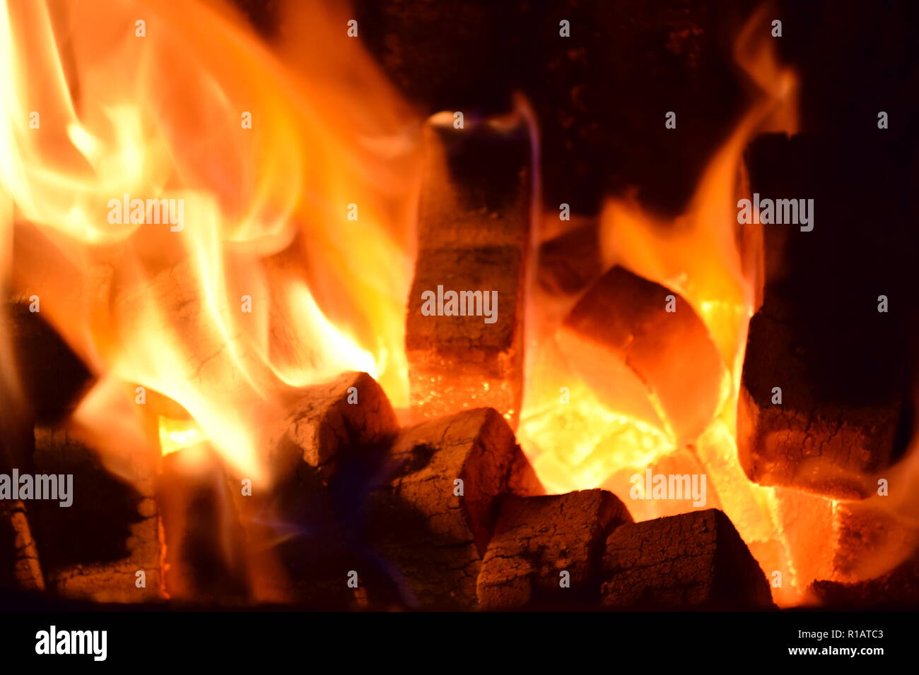 Close up of Brown Coal Briquettes on fire with red yellow flames inside ...