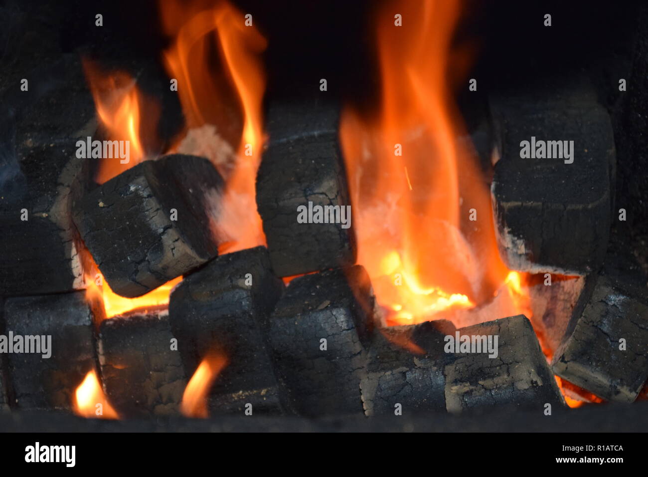 Close up of Brown Coal Briquettes on fire with red yellow flames inside ...