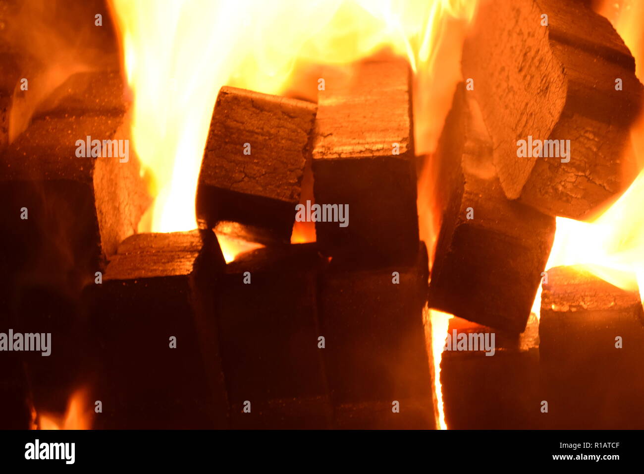 Close up of Brown Coal Briquettes on fire with red yellow flames inside ...