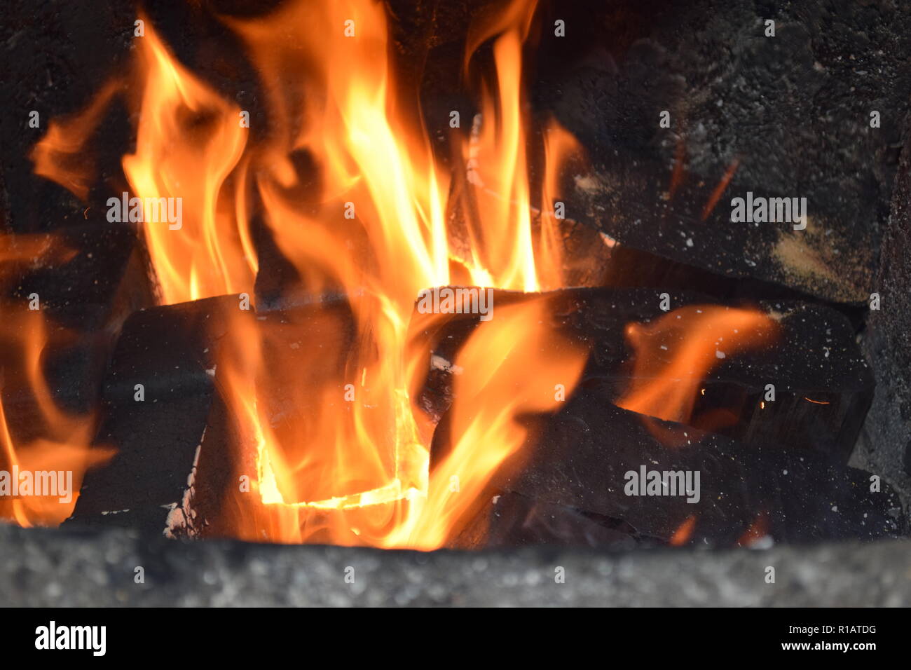Close up of Brown Coal Briquettes on fire with red yellow flames inside ...