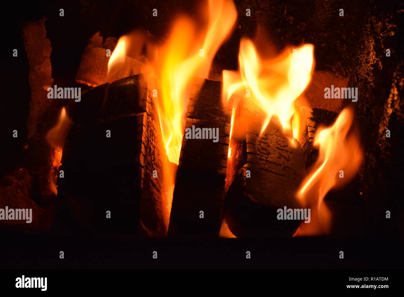Close up of Brown Coal Briquettes on fire with red yellow flames inside ...