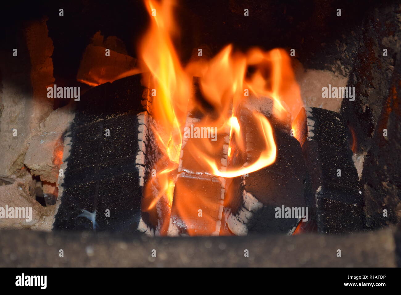 Close up of Brown Coal Briquettes on fire with red yellow flames inside ...