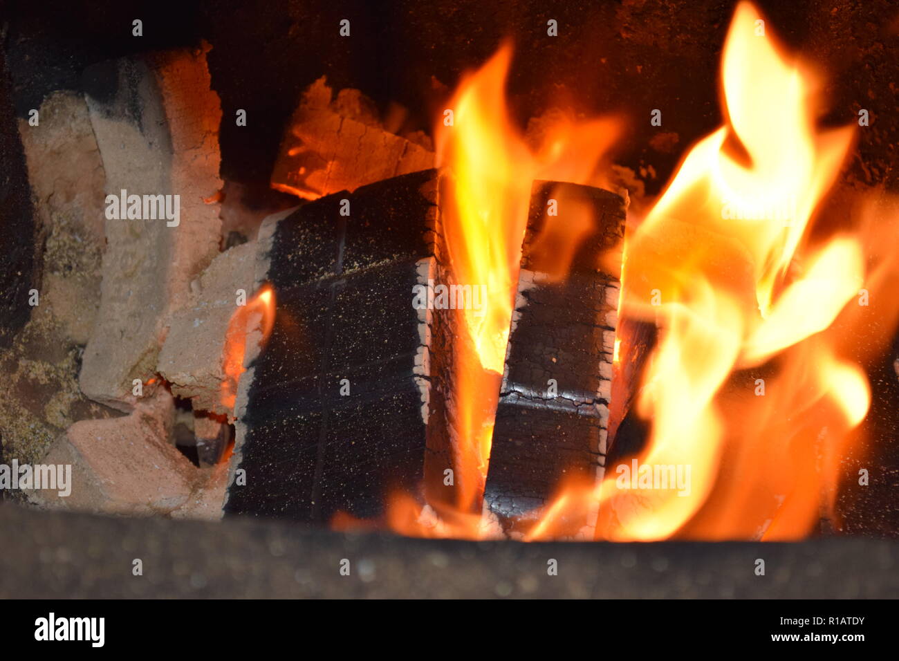 Close up of Brown Coal Briquettes on fire with red yellow flames inside ...