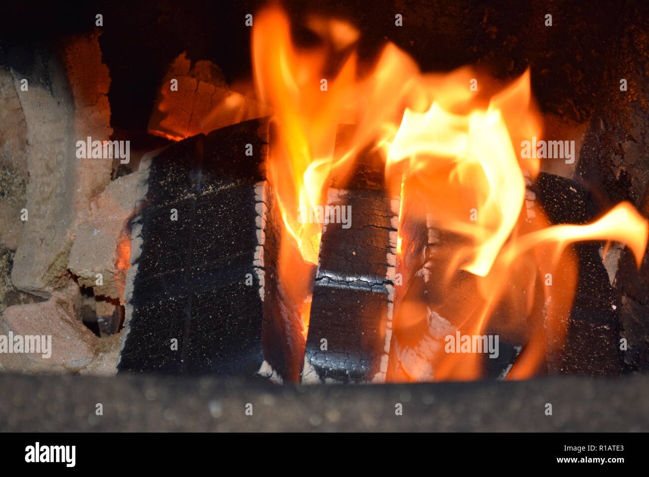 Close up of Brown Coal Briquettes on fire with red yellow flames inside ...