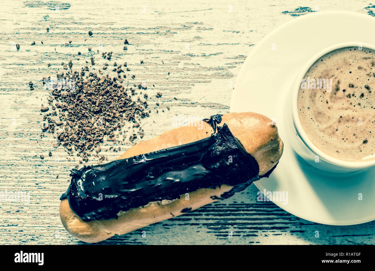 Coffee, cake, eclair with chocolate chips close-up on vintage wooden ...