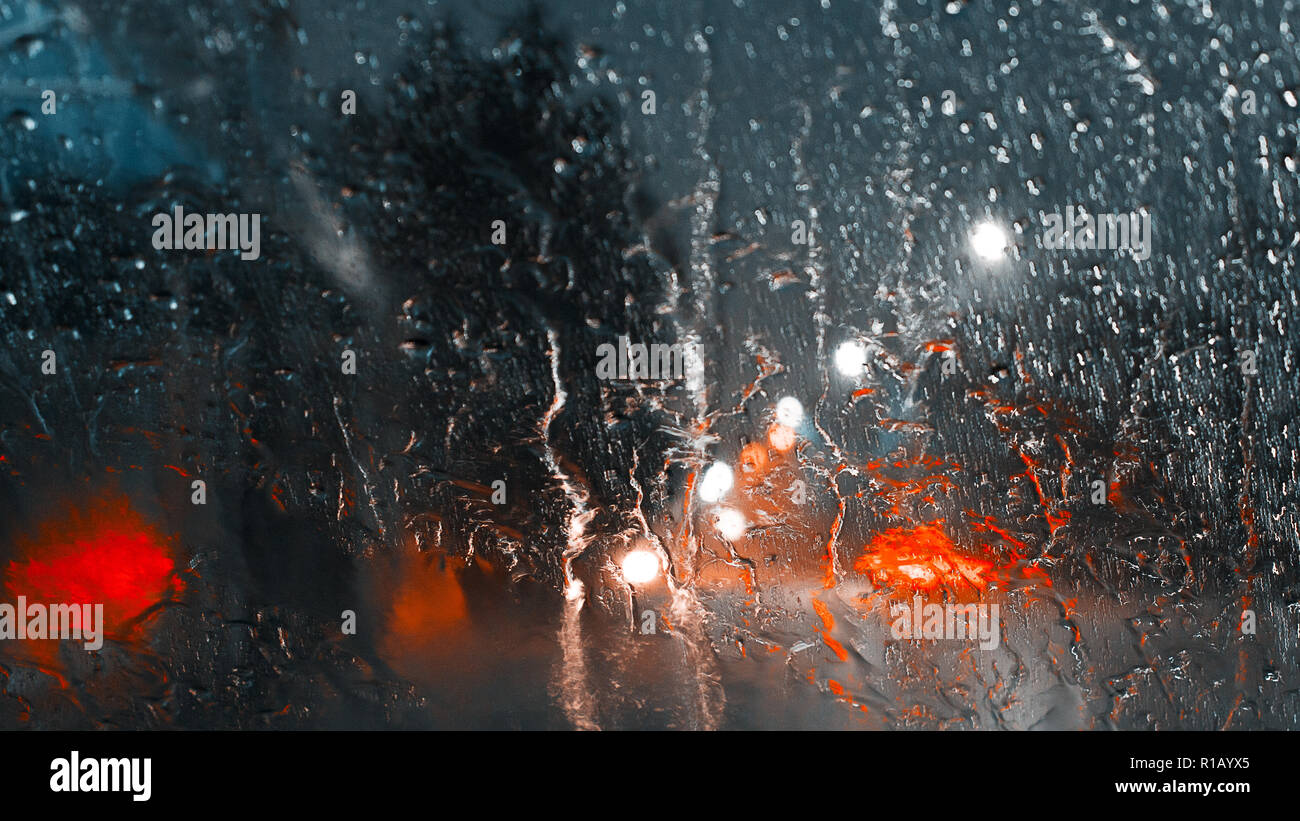 Abstract image of drops of rain on window with night reflections lights ...