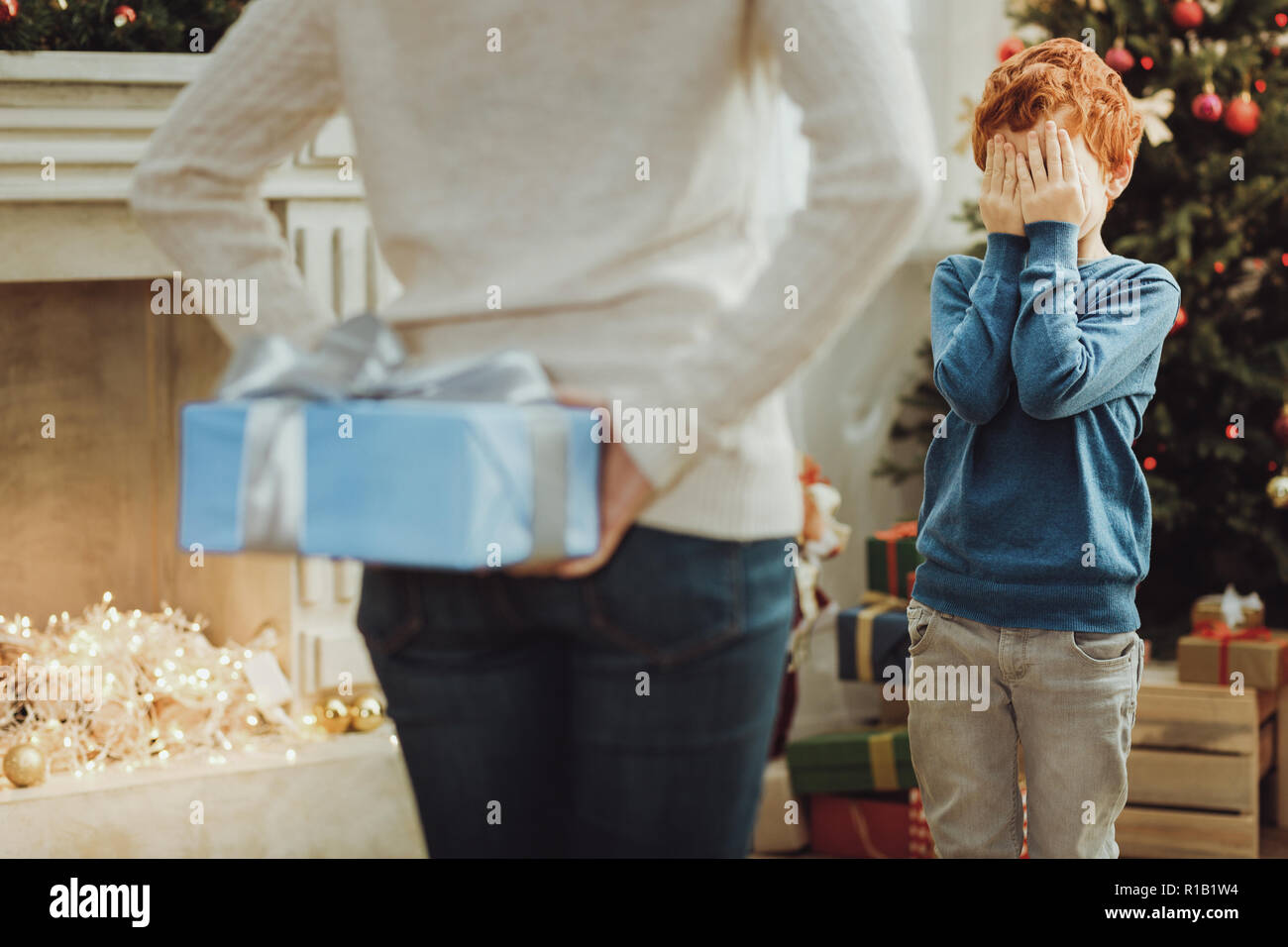 Back view picture of happy mother that hiding present Stock Photo - Alamy