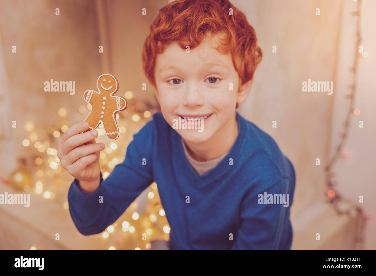 Smiling red-haired boy showing gingerbread man Stock Photo - Alamy