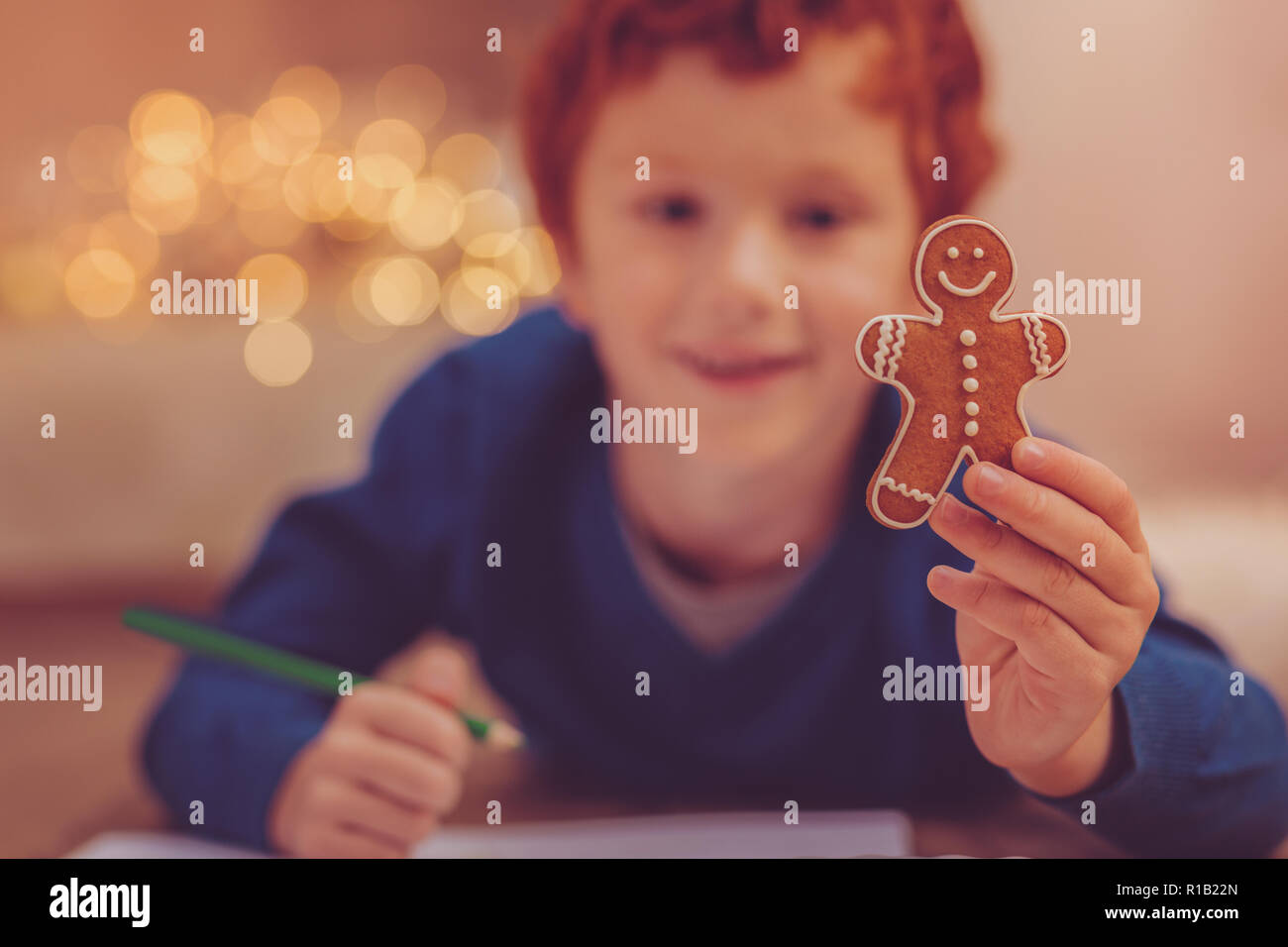 Red-haired boy showing gingerbread man while drawing it Stock Photo - Alamy