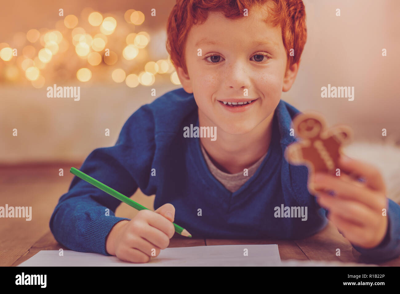 Cute boy holding gingerbread man and drawing it Stock Photo - Alamy