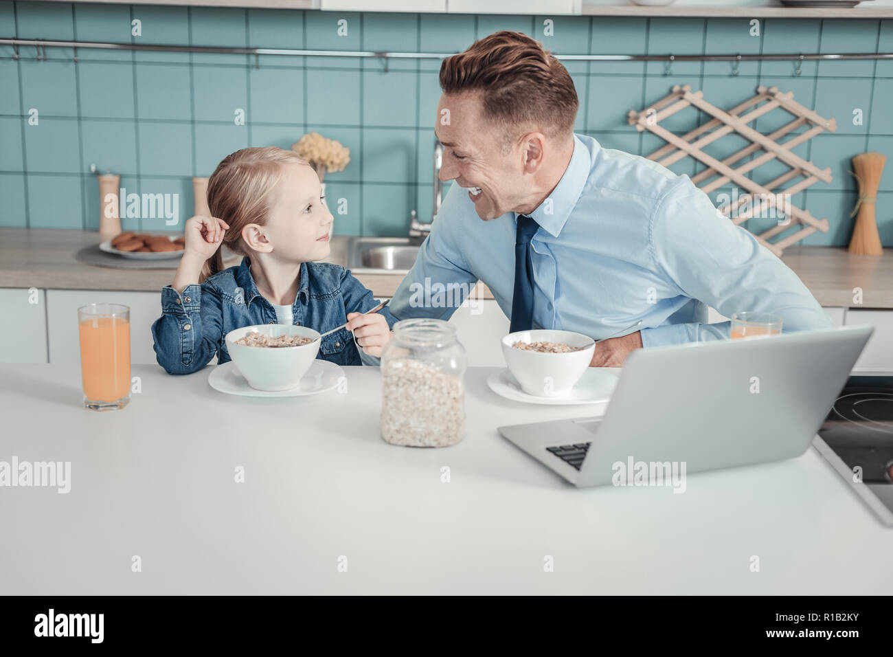 Lovely attentive father sitting and smiling to his daughter Stock Photo ...
