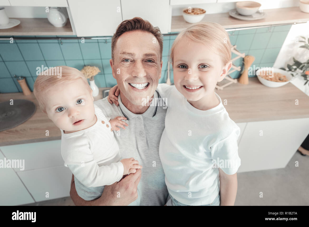Satisfied happy daddy holding children and rejoicing Stock Photo - Alamy