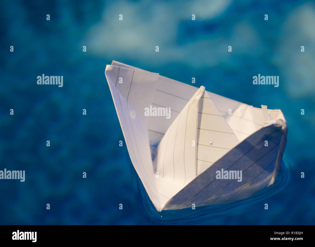 Paper boat floating on blue water Stock Photo - Alamy