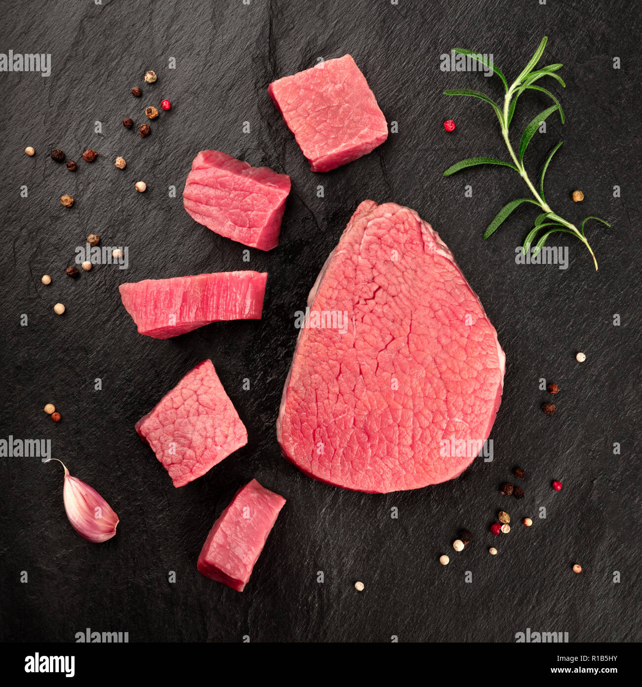 Slices of eye round beef, a raw cut, with rosemary, garlic, and ...