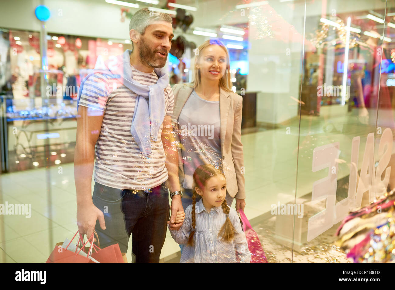 Portrait of happy family looking at window displays while shopping in ...