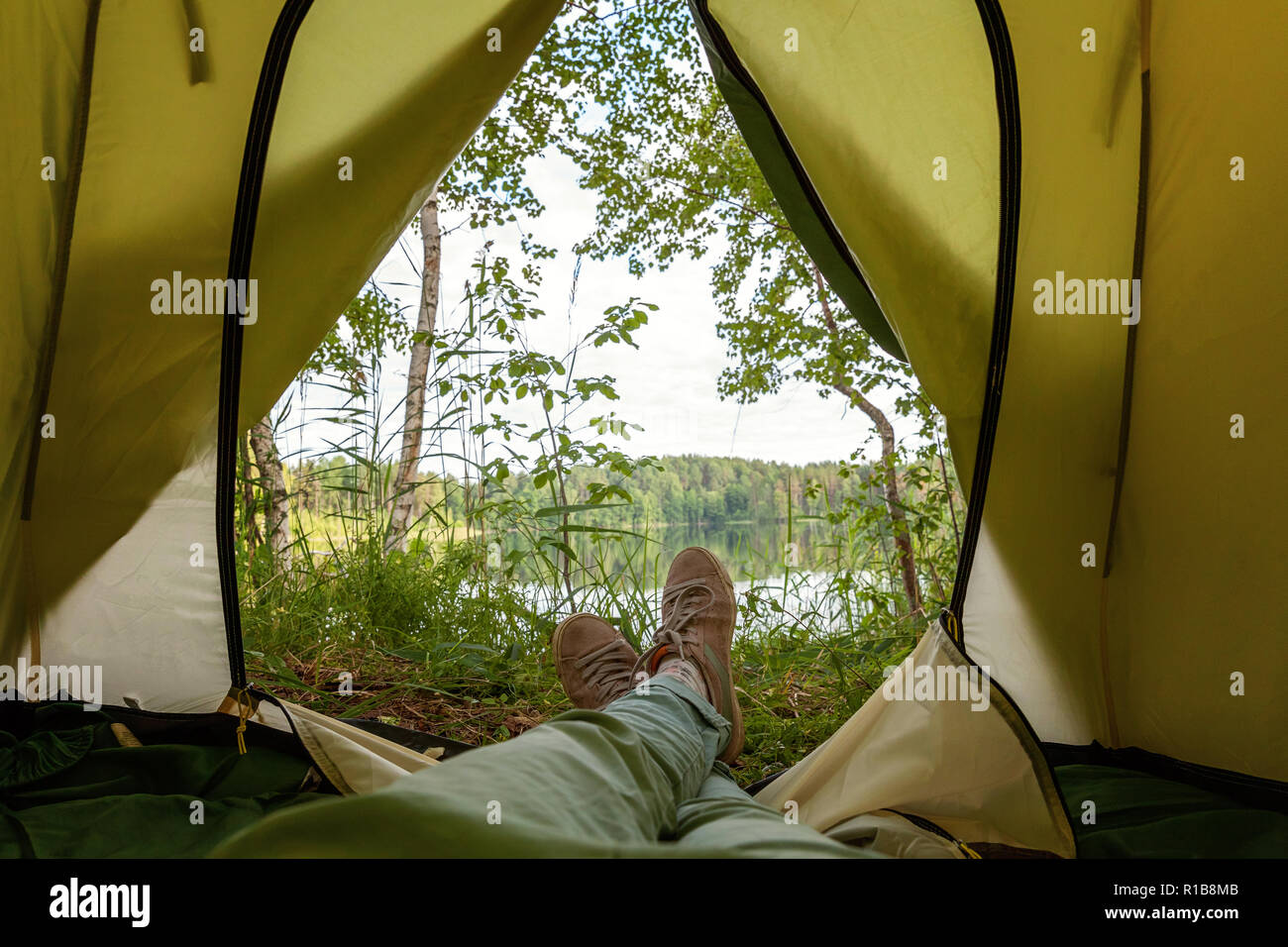 Photo of woman legs in green jeans and sneakers laying in tourist tent ...